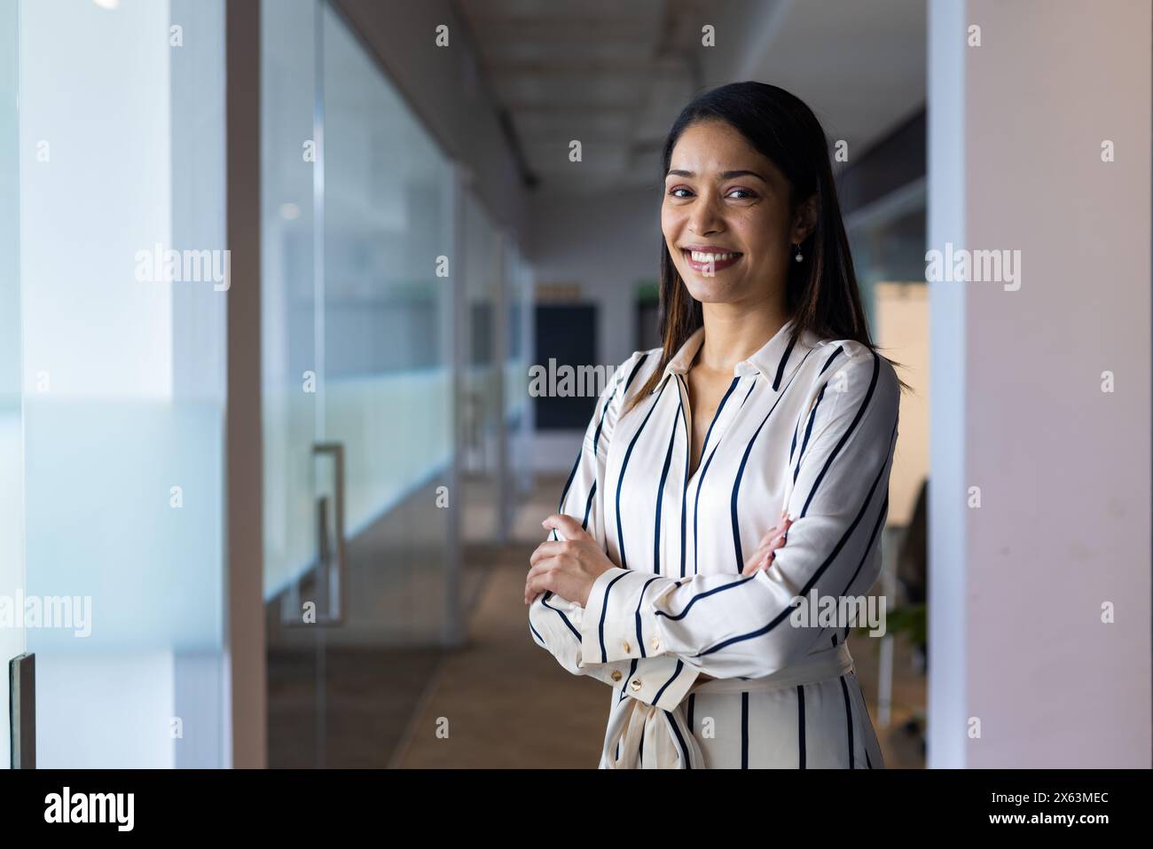 Middle-aged biracial female manager standing with arms crossed at ...