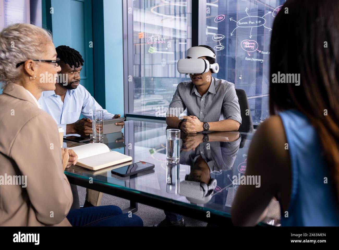A diverse team meeting at office, one wearing virtual reality headset ...