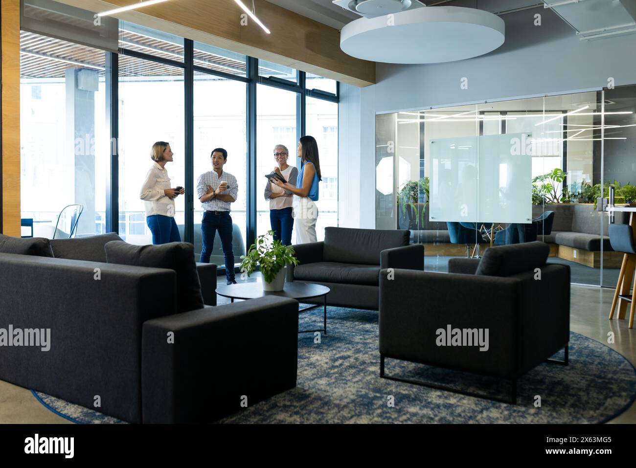 Diverse team standing, talking in modern office lounge, copy space ...