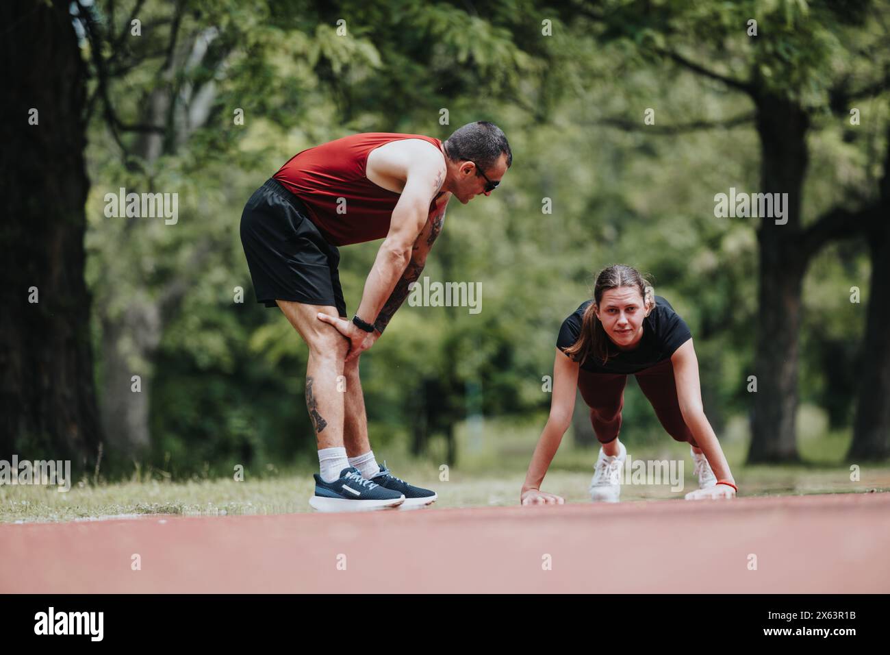 Athletic man and woman in a race starting position on a track, focusing ...