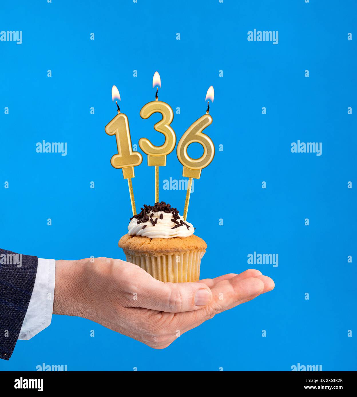 Hand delivering birthday cupcake - Candle number 136 on blue background ...