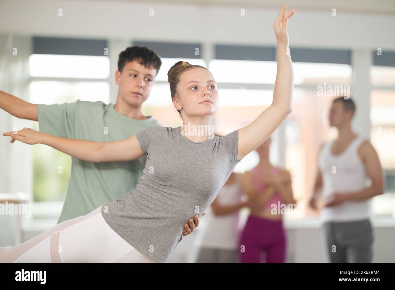Teenage girl practicing ballet positions in pair with boy in dance ...