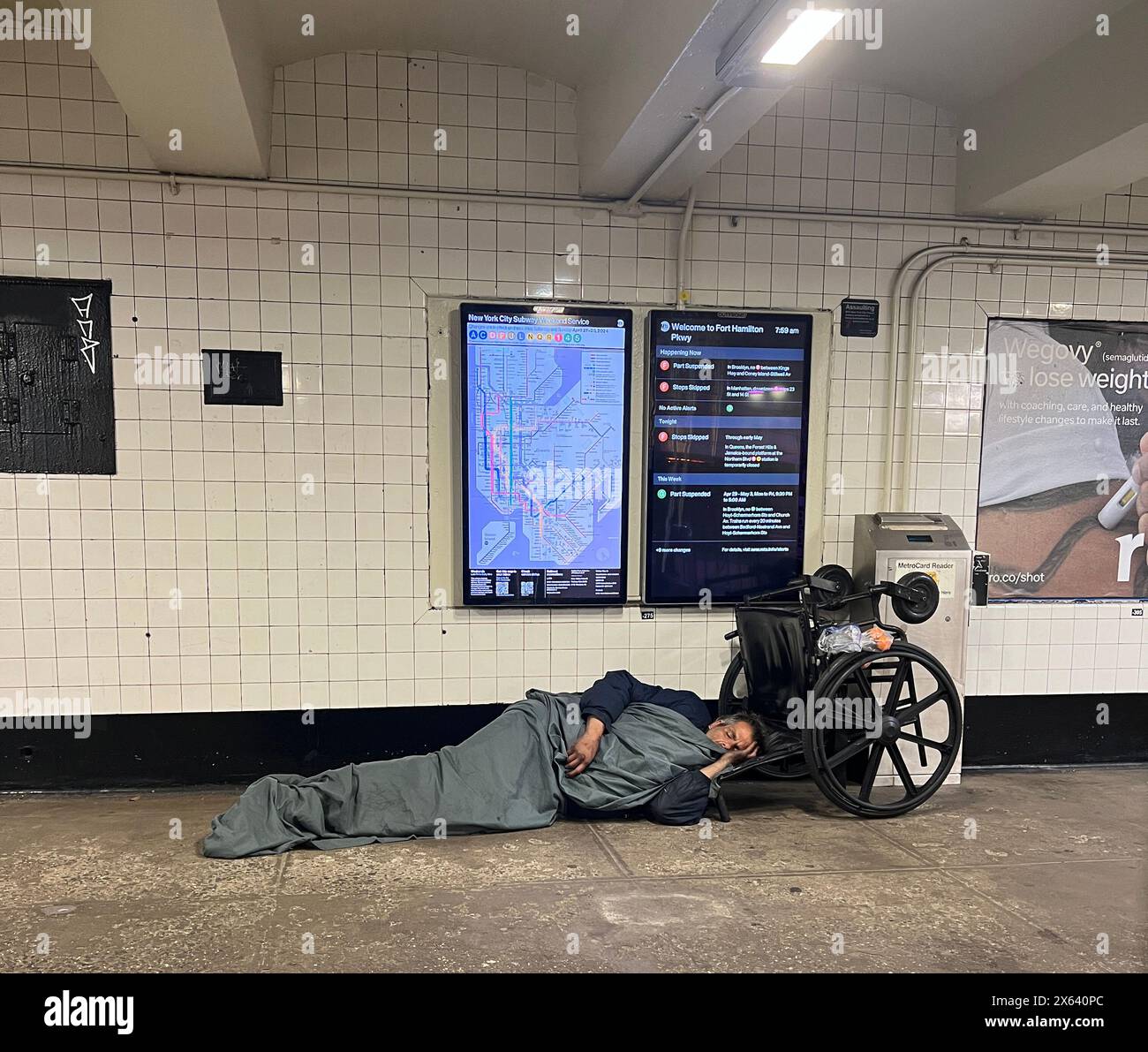 Disabled homeless man sleeps in a subway train station entrance by his ...