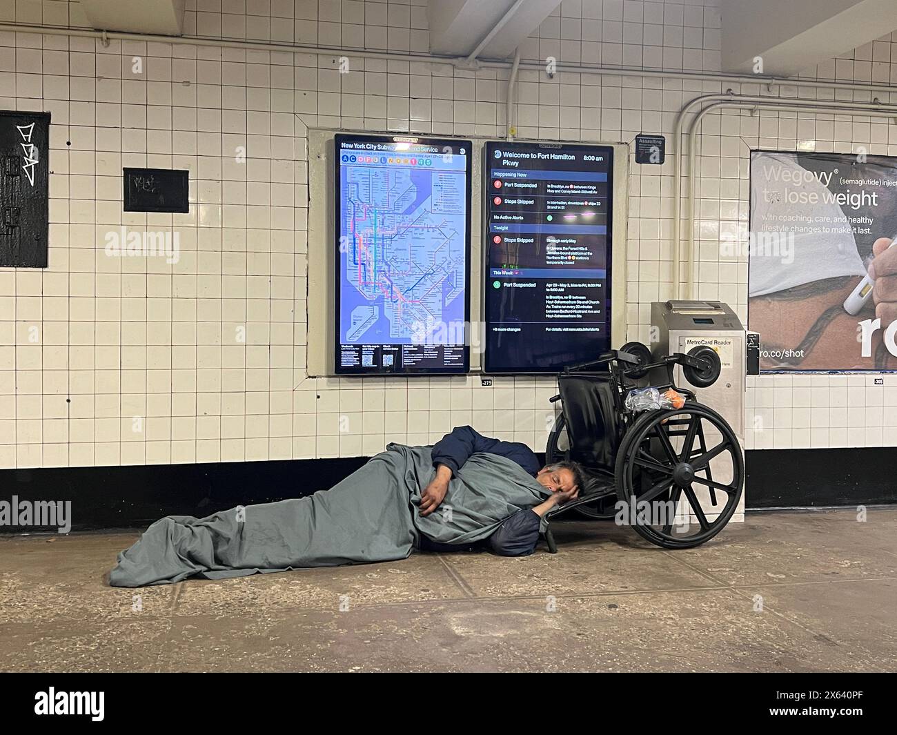 Disabled homeless man sleeps in a subway train station entrance by his ...