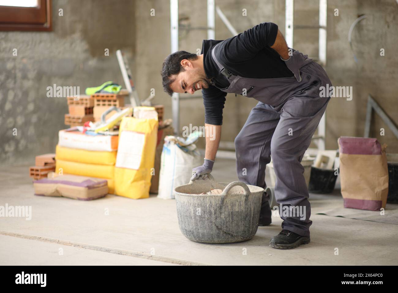 Construction worker suffering back ache and complaining trying to lift ...