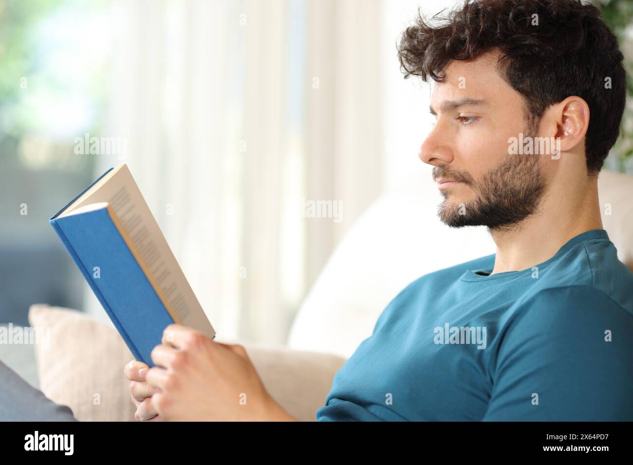 Side view portrait of a serious man reading a paper book sitting on a ...