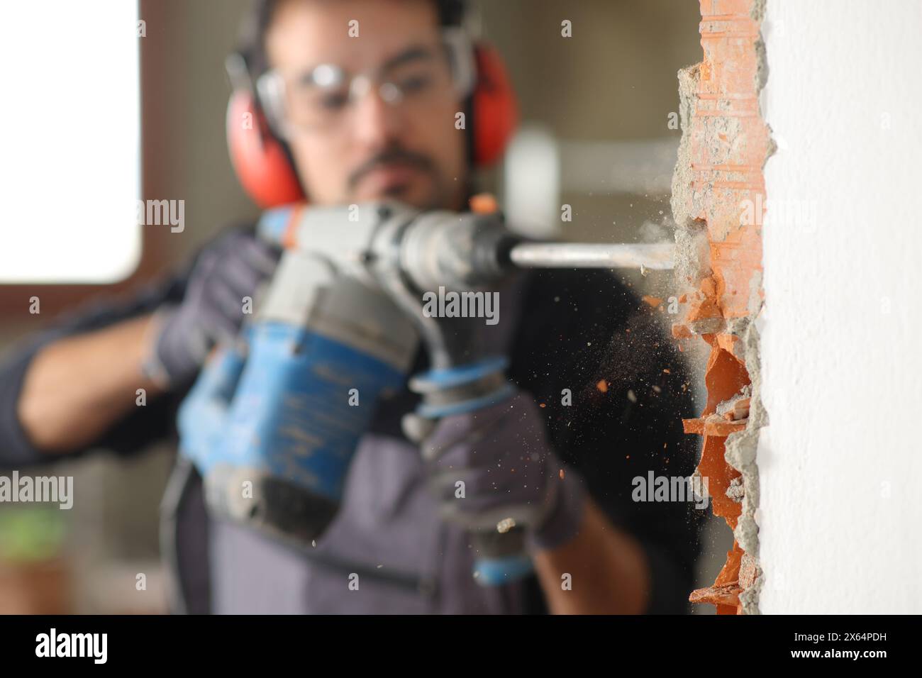 Construction worker using a rotary hammer to wreck a wall in a house ...