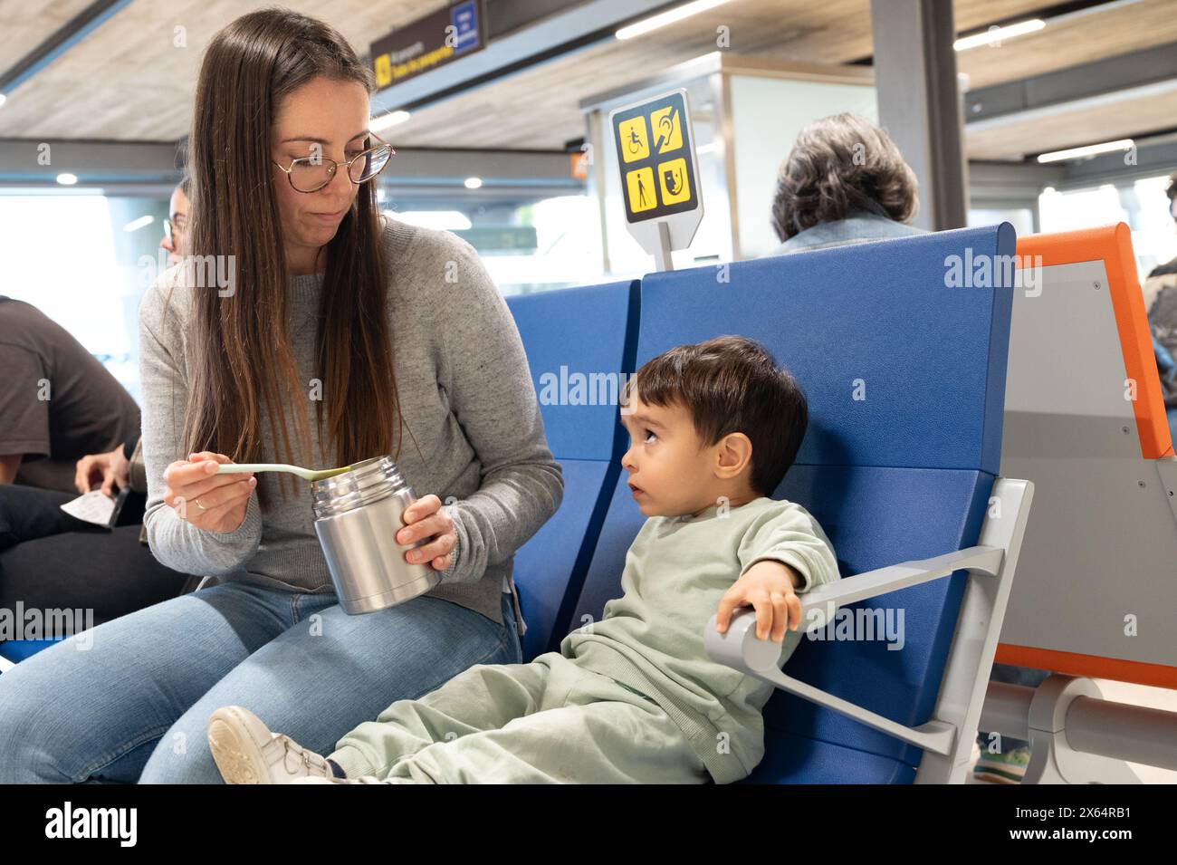 A woman is feeding a child a spoonful of food. The child is sitting on ...