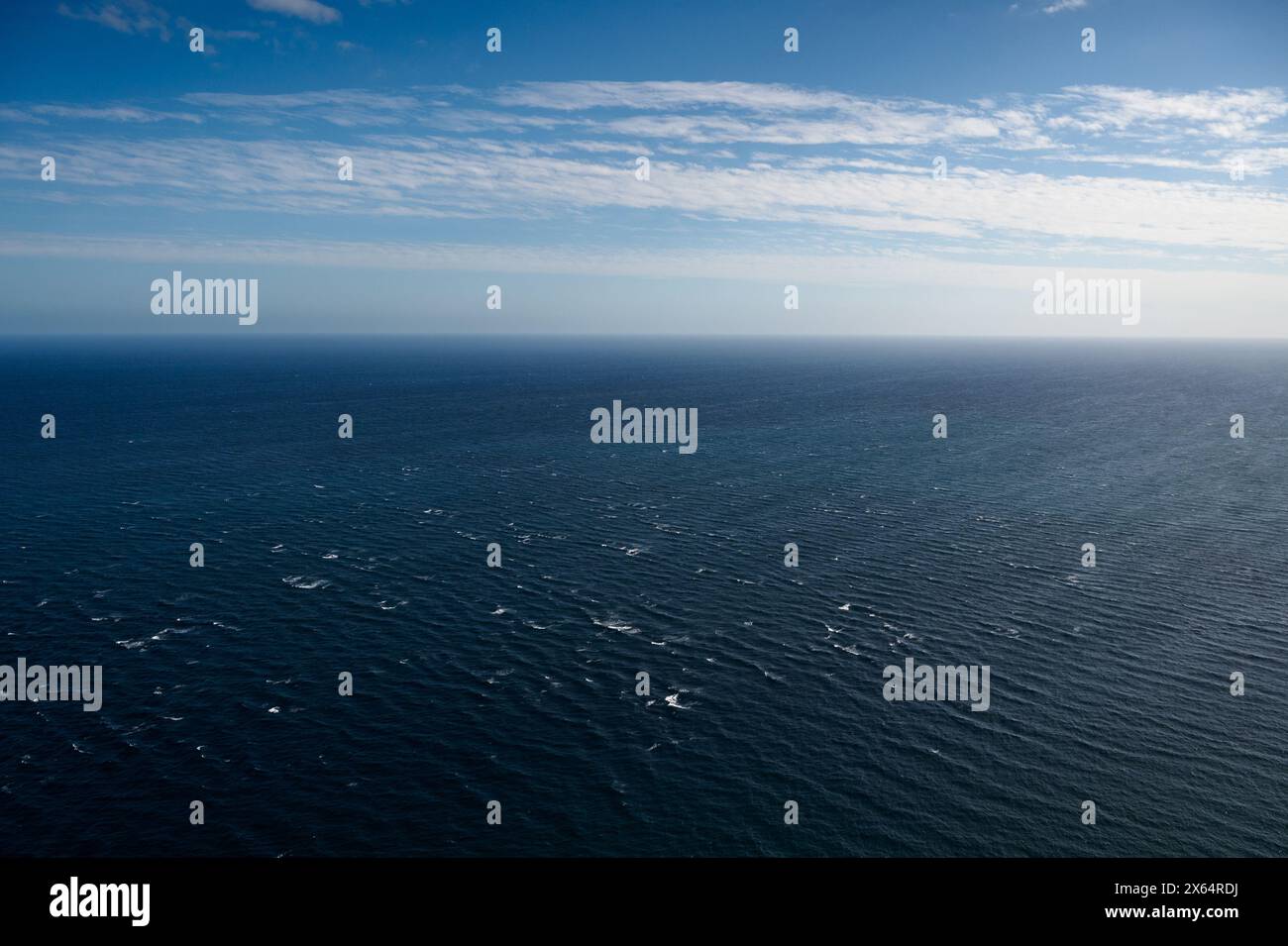 The sky is clear and the ocean is calm. The water is a deep blue color ...