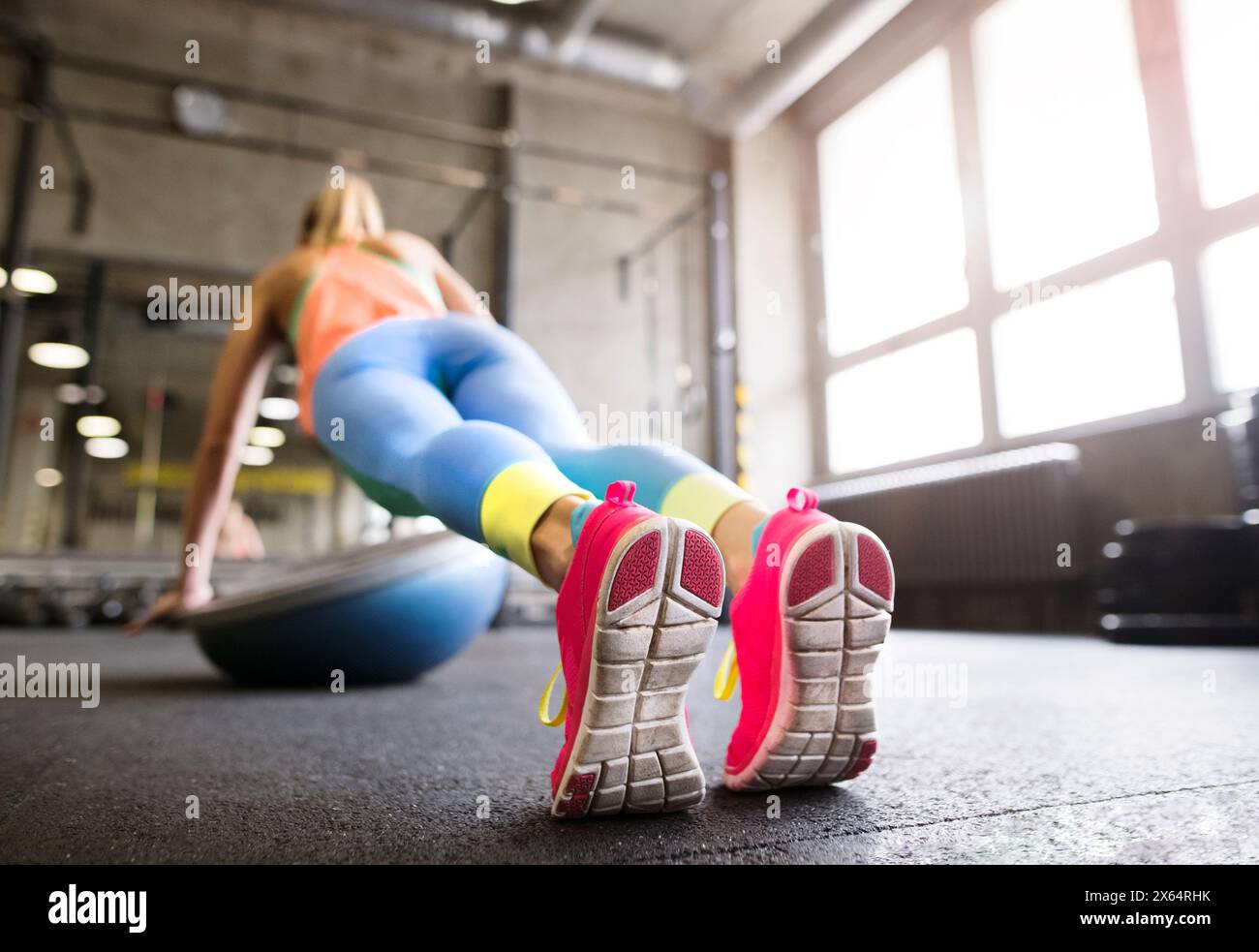 Beautiful sport woman exercising on balance ball in gym, doing pushups ...