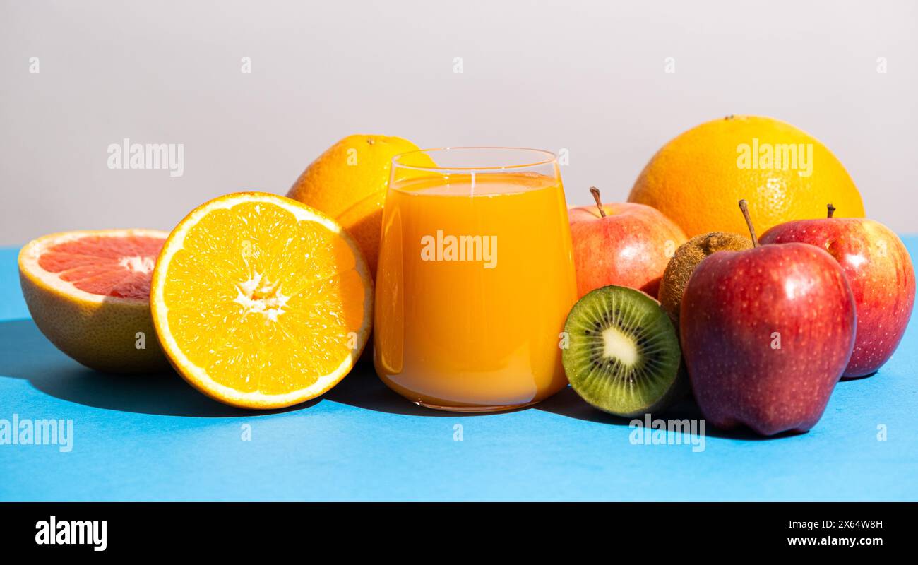 Multifruit juice in a glass among fresh fruits on blue and white ...