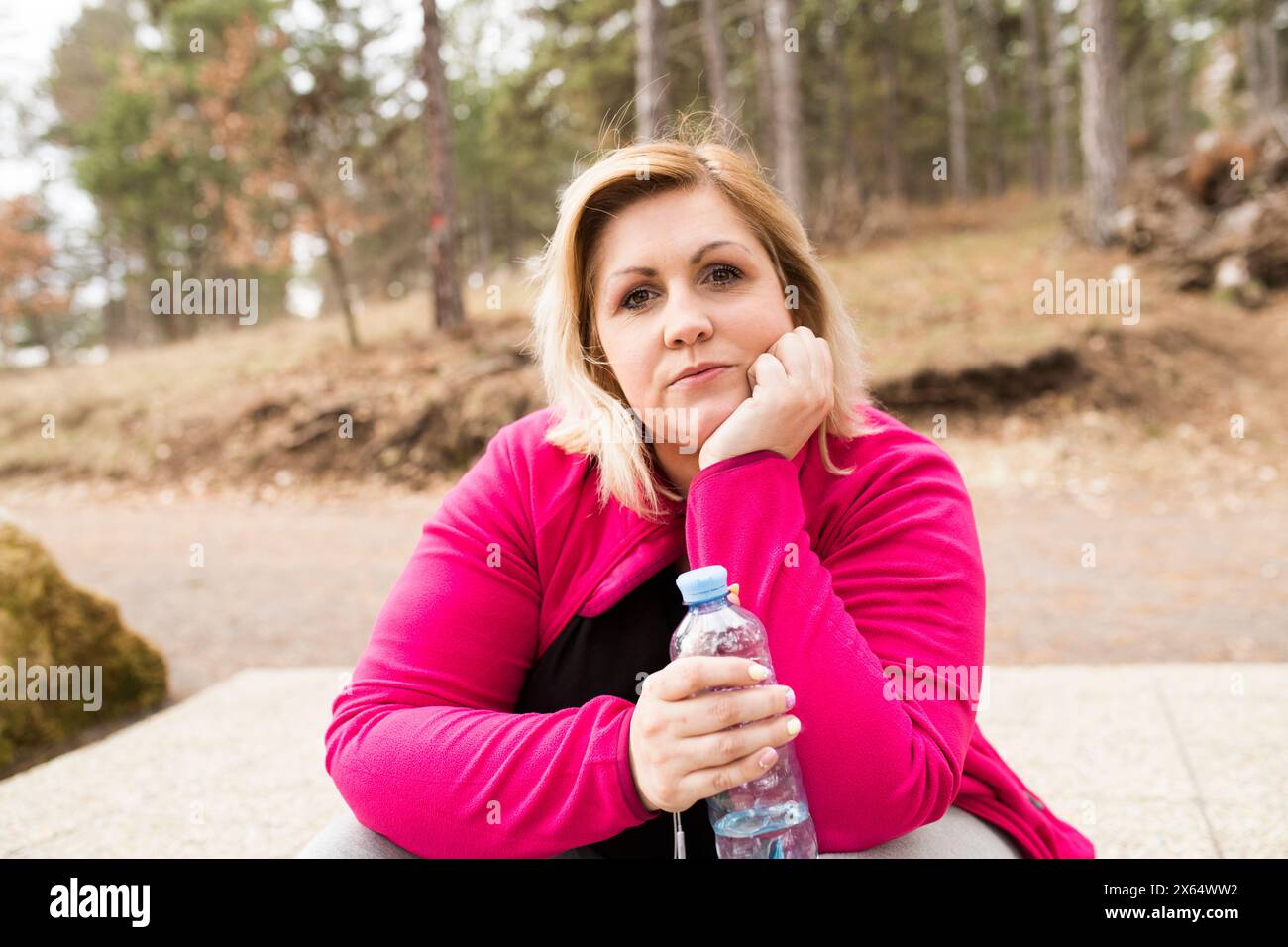Overweight woman drinking water after run in nature. Exercising ...