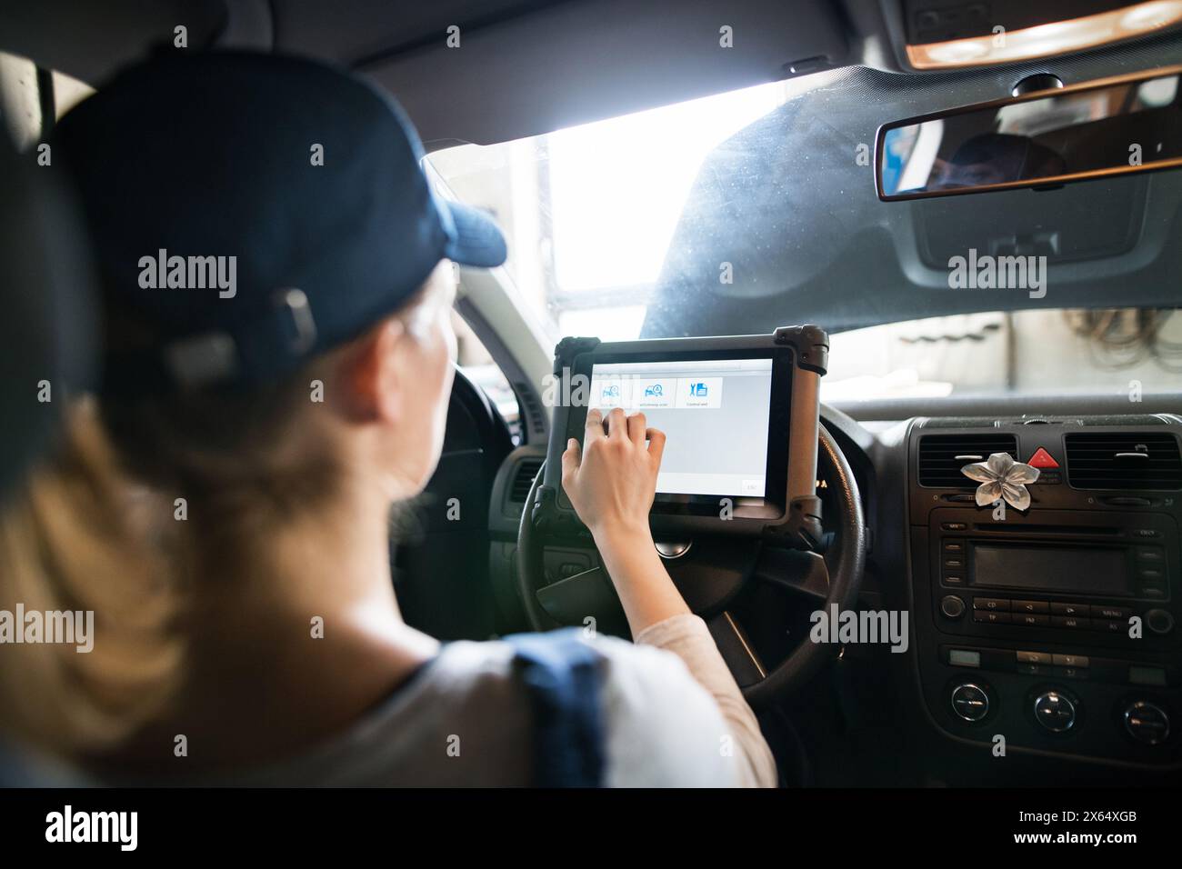 Female auto mechanic using diagnostic tool, scanner, running diagnostic ...