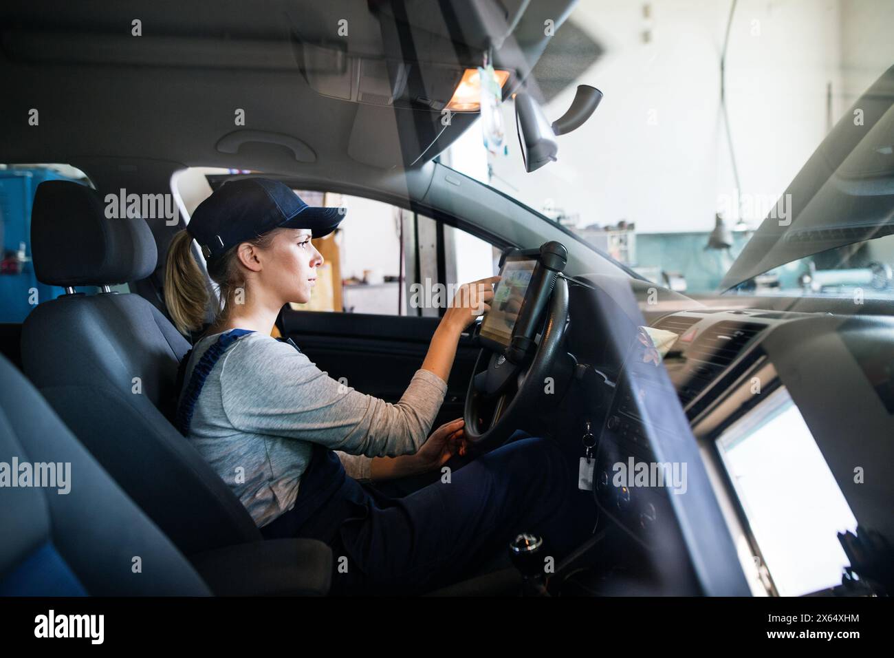 Female auto mechanic using diagnostic tool, scanner, running diagnostic ...