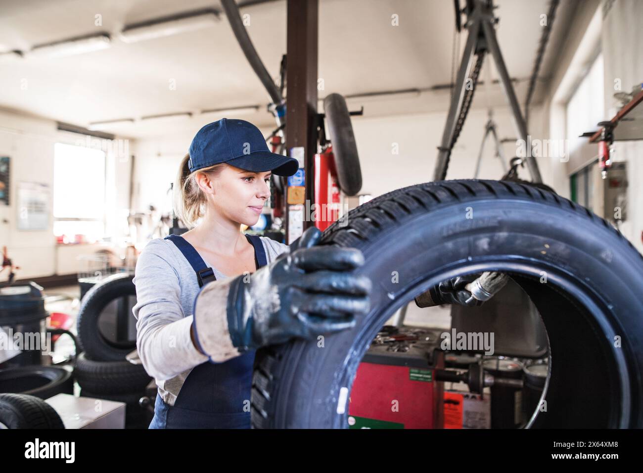 Female auto mechanic changing tieres in auto service. Beautiful woman ...