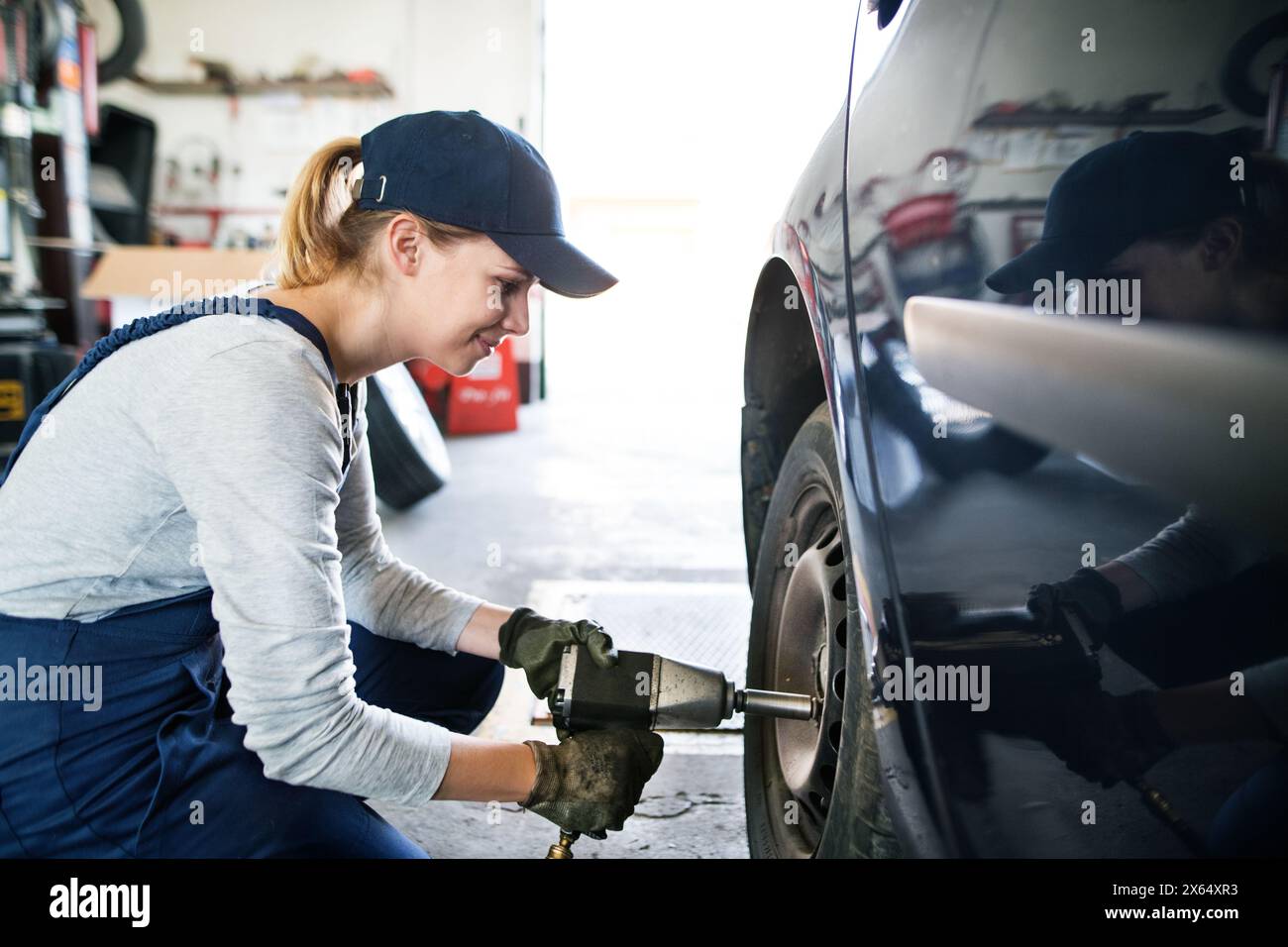 Female auto mechanic changing tieres in auto service. Beautiful woman ...