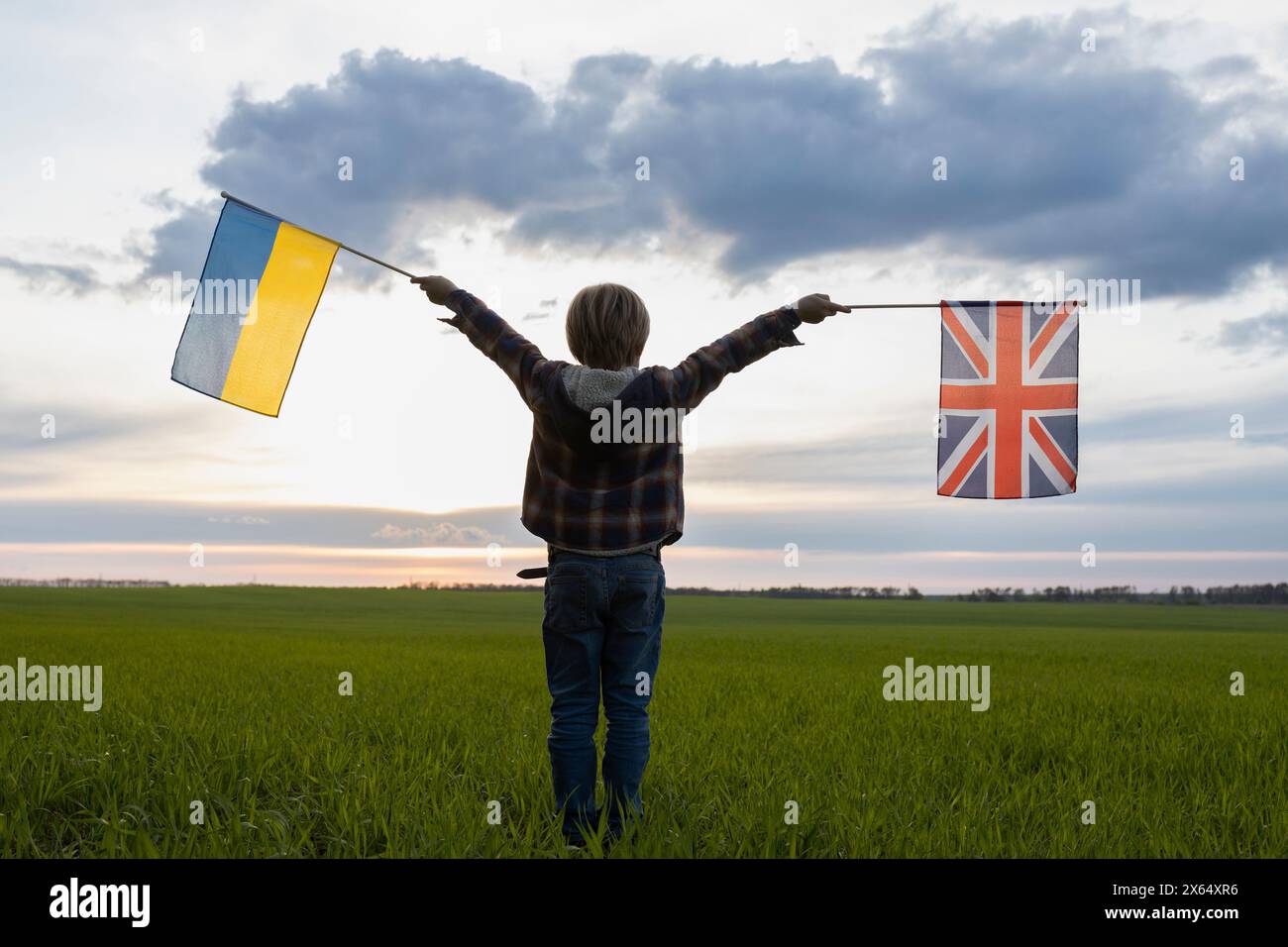 unrecognizable child holds British and Ukrainian flags against of the ...