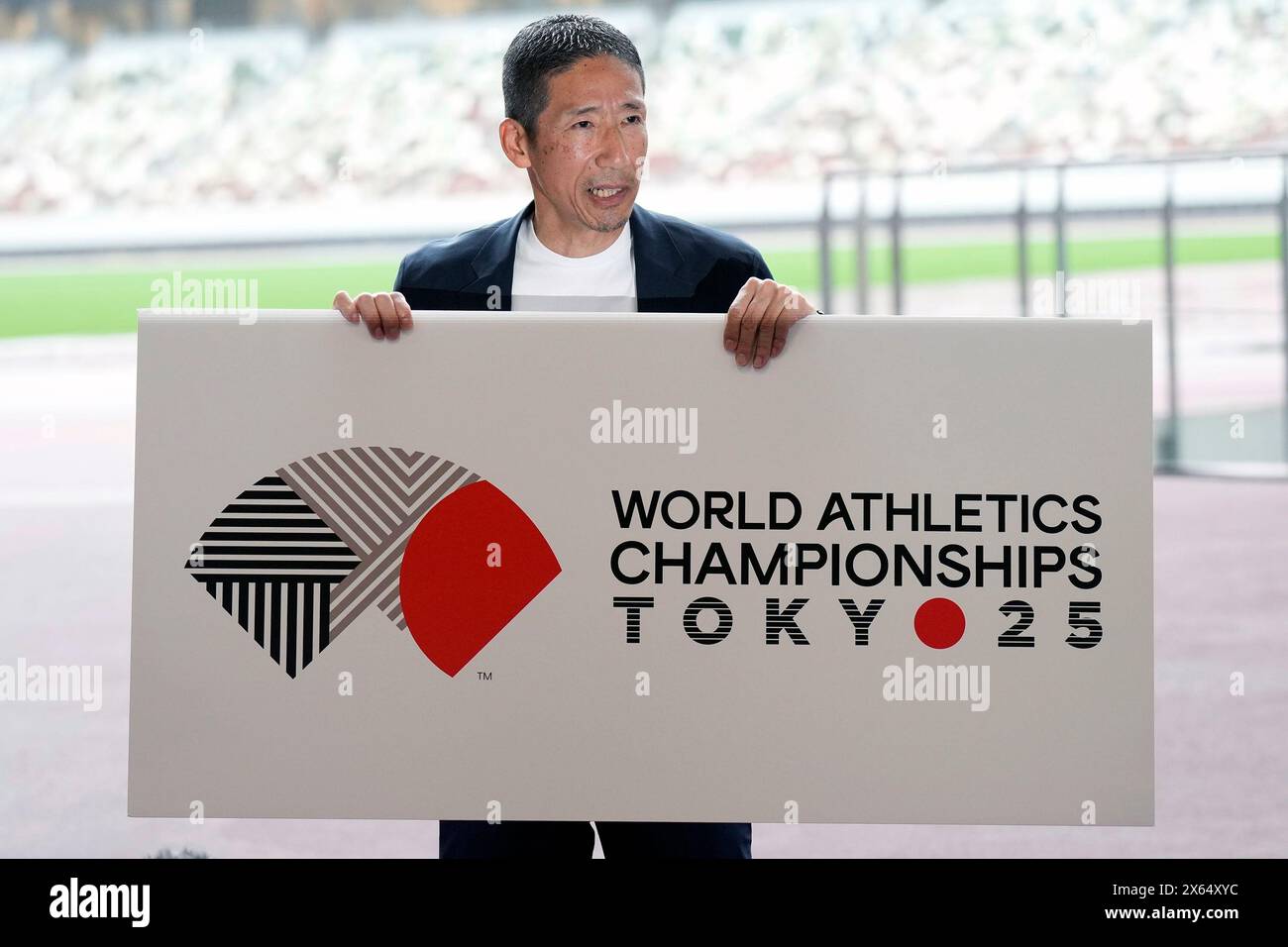 Japanese designer Ryo Nakagawa poses with a banner of the official logo ...