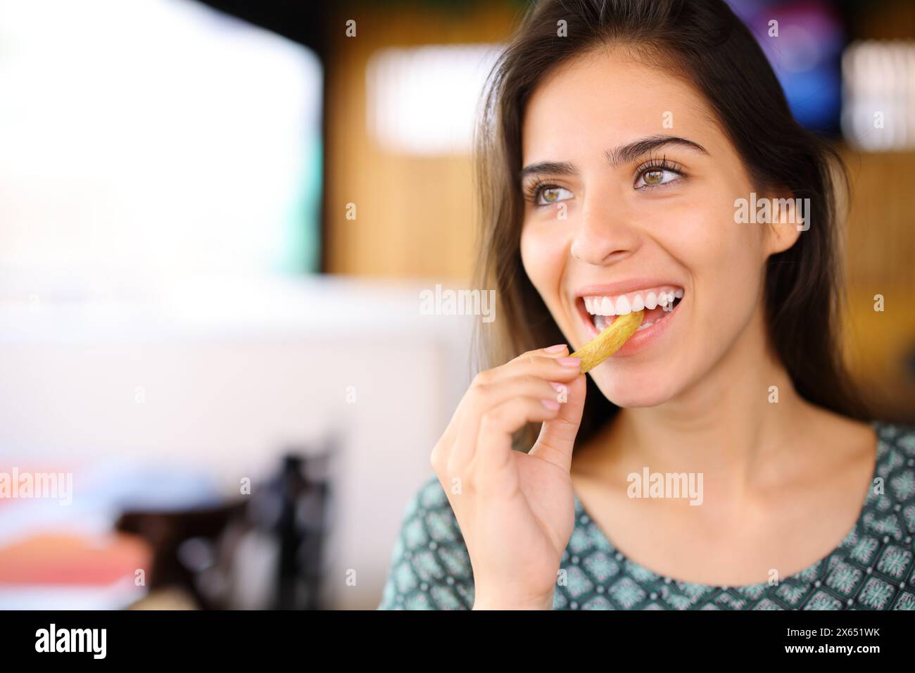 Happy woman eating potato in a restaurant looking away Stock Photo - Alamy