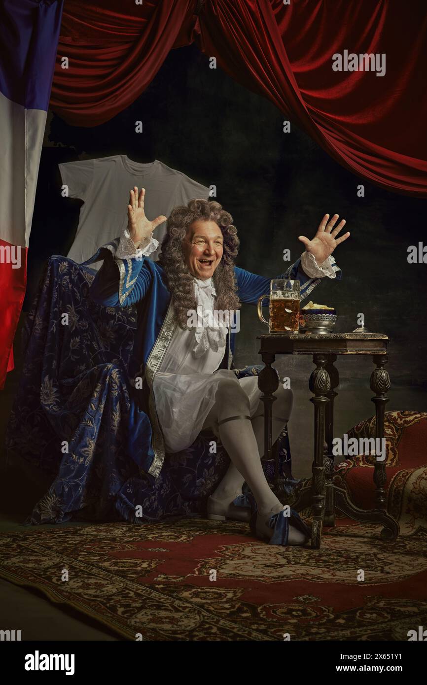 Delightful, happy man dressed as king in old-fashioned attire watching ...