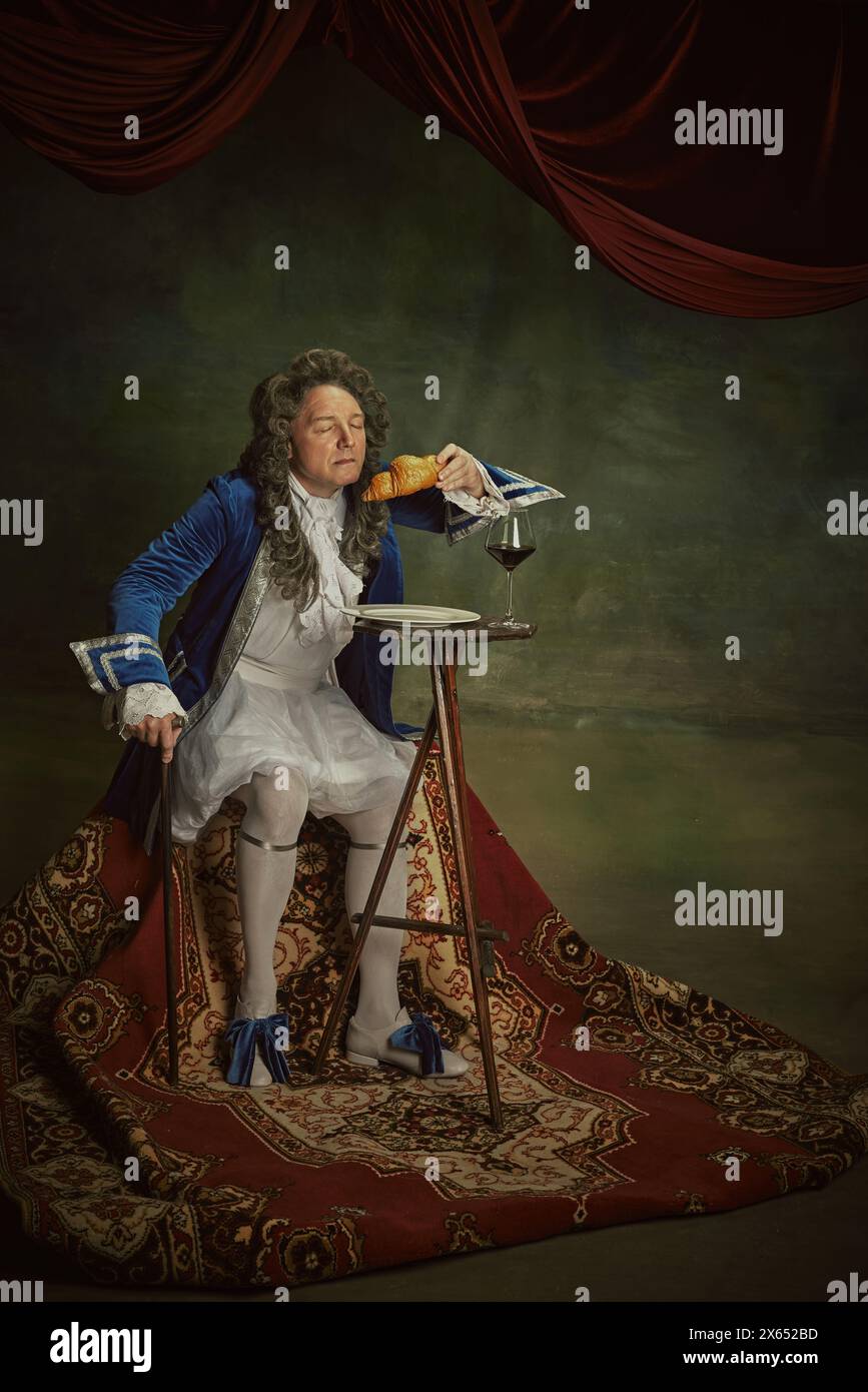 Elderly man in classical baroque attire have breakfast, eating ...