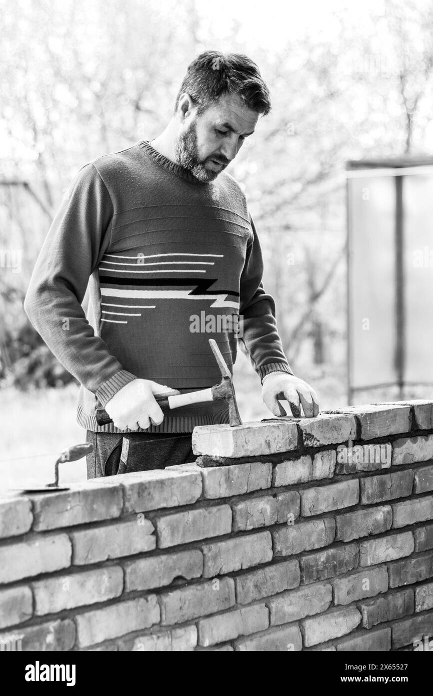 a man builds a brick wall, puts a brick on a cement-sand mortar ...