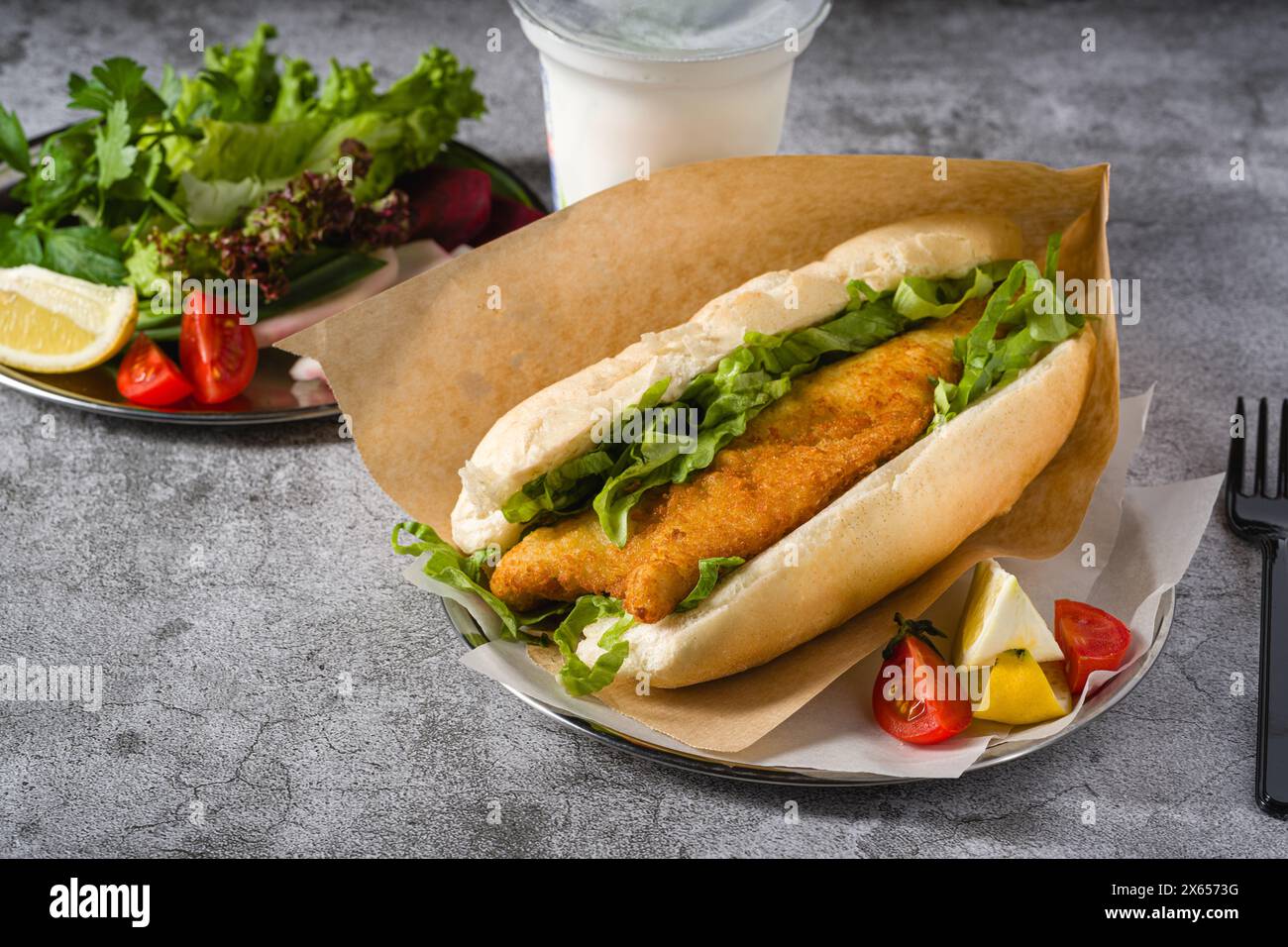 Fried fish sandwich with greens on the stone table. Turkish name Balik ...