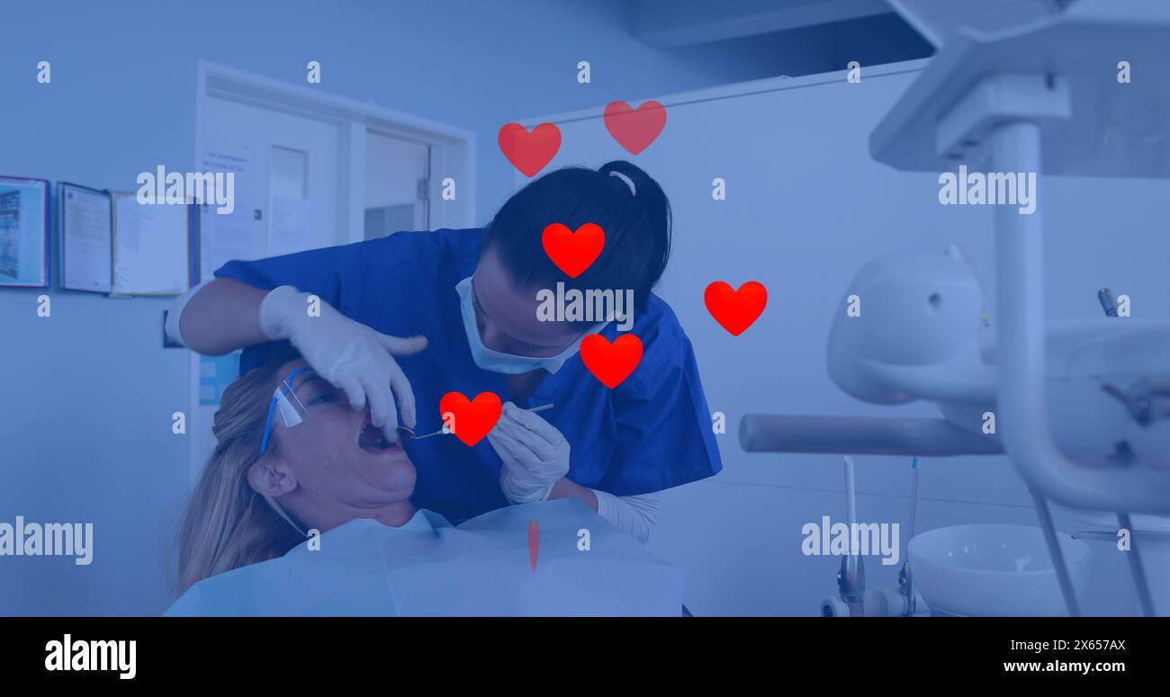 Image of heart icons over biracial female dentist treating caucasian ...