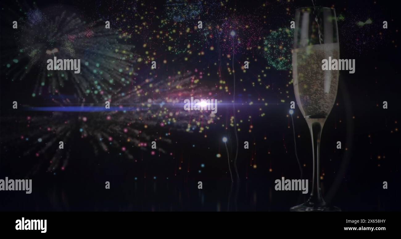 A glass of champagne standing with fireworks bursting in background ...