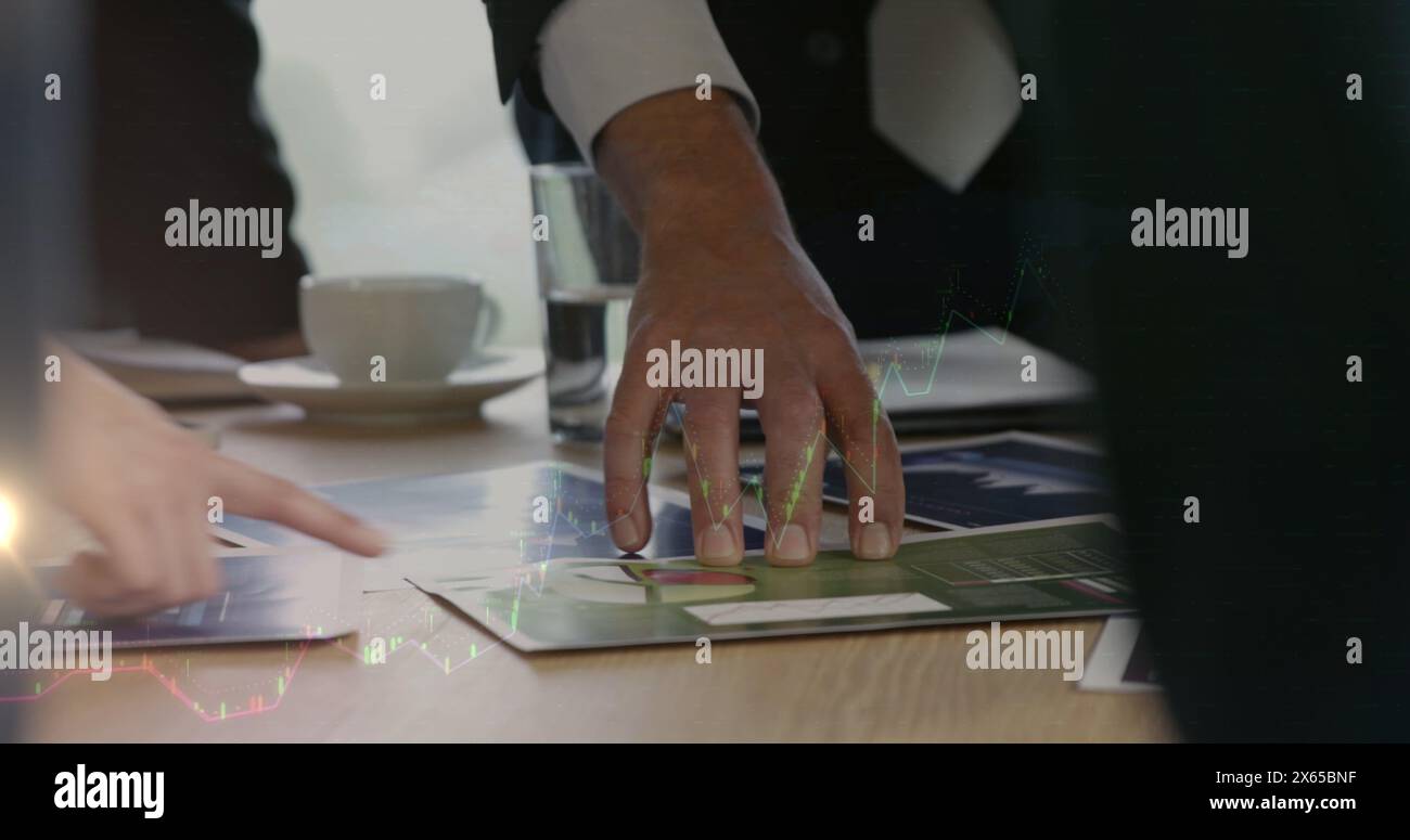 Multiple people standing around table, examining documents and charts ...
