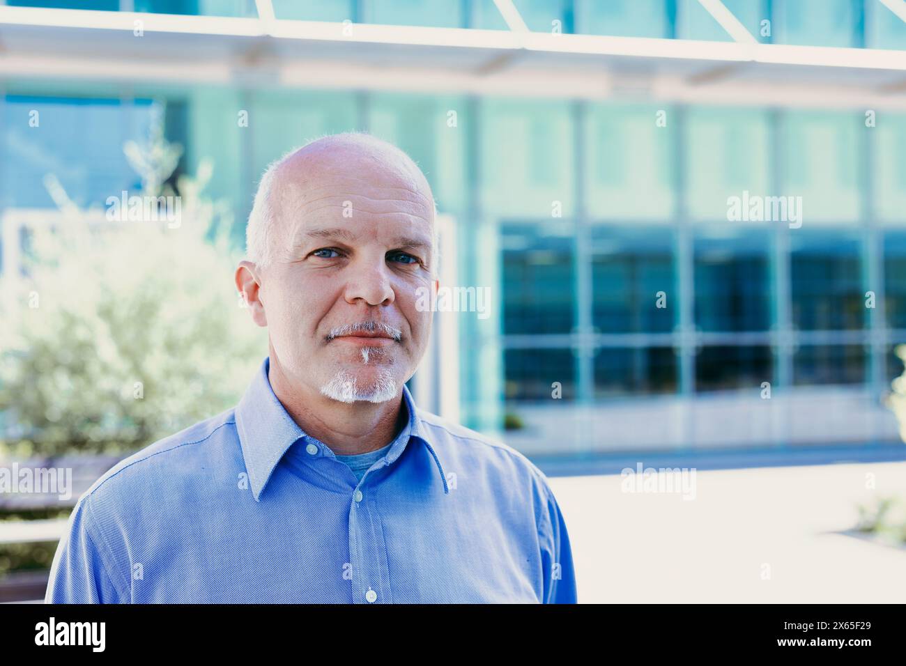 Middle-aged professional stands outdoors with a modern architectural ...