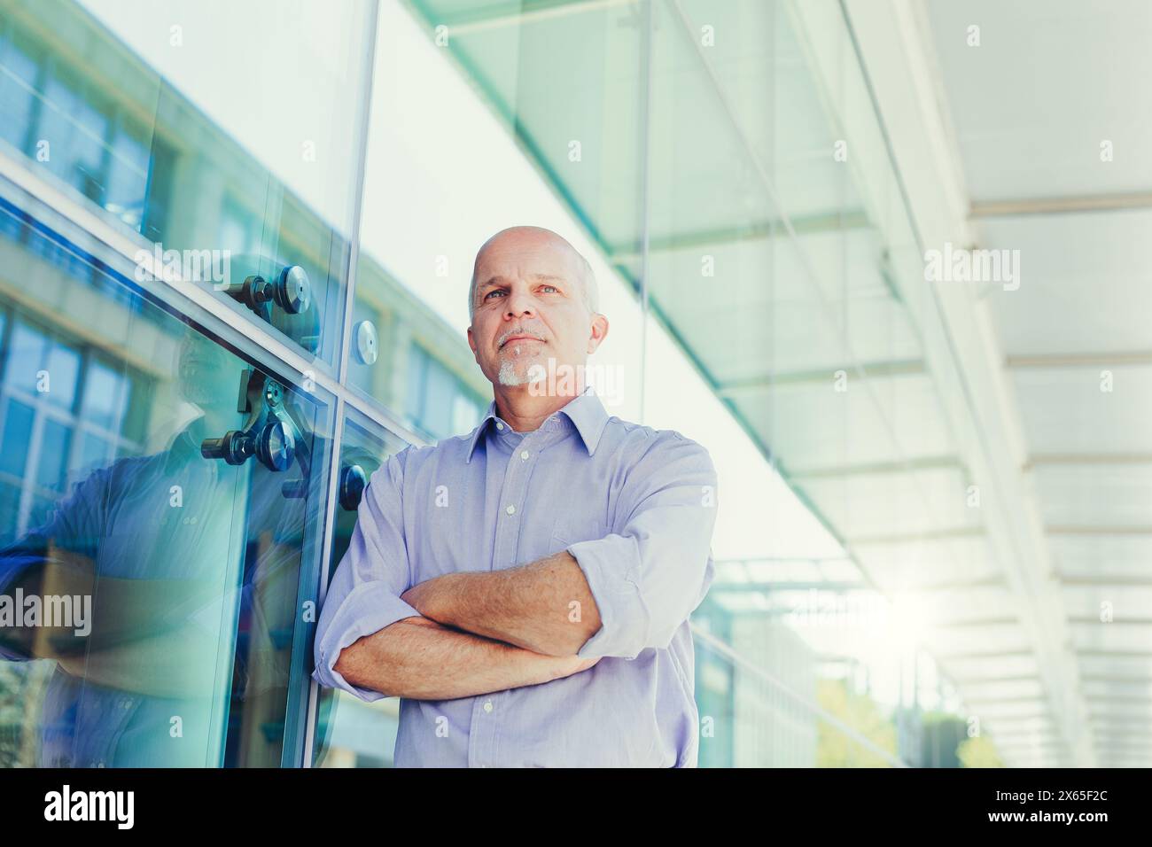Elderly executive outside a glass facade building, his expression ...