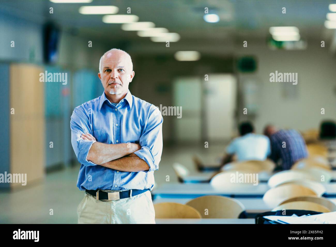 Seasoned professional poses with crossed arms in a glass-walled office ...