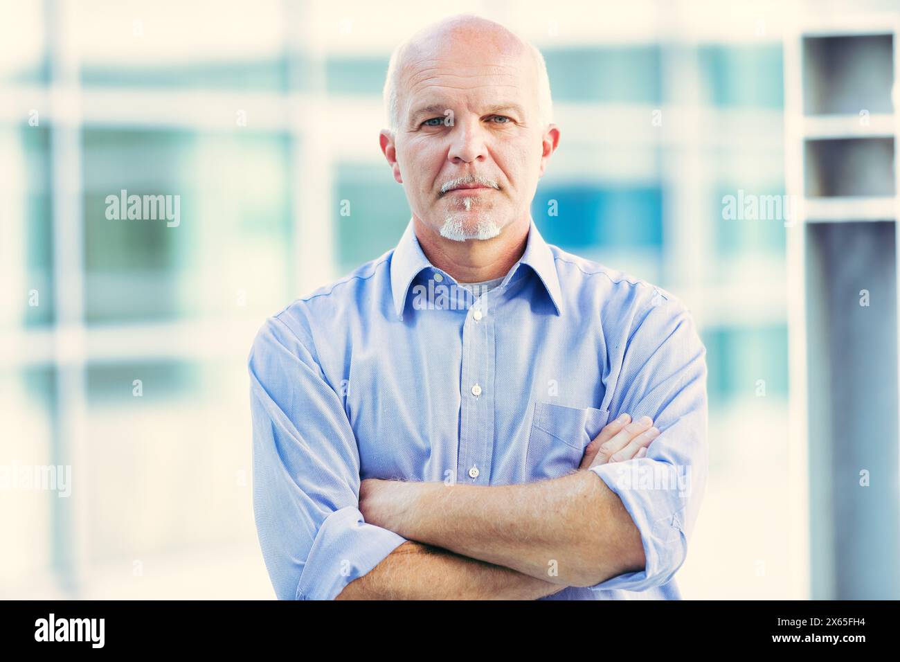 Senior professional stands confidently with arms crossed in front of a ...