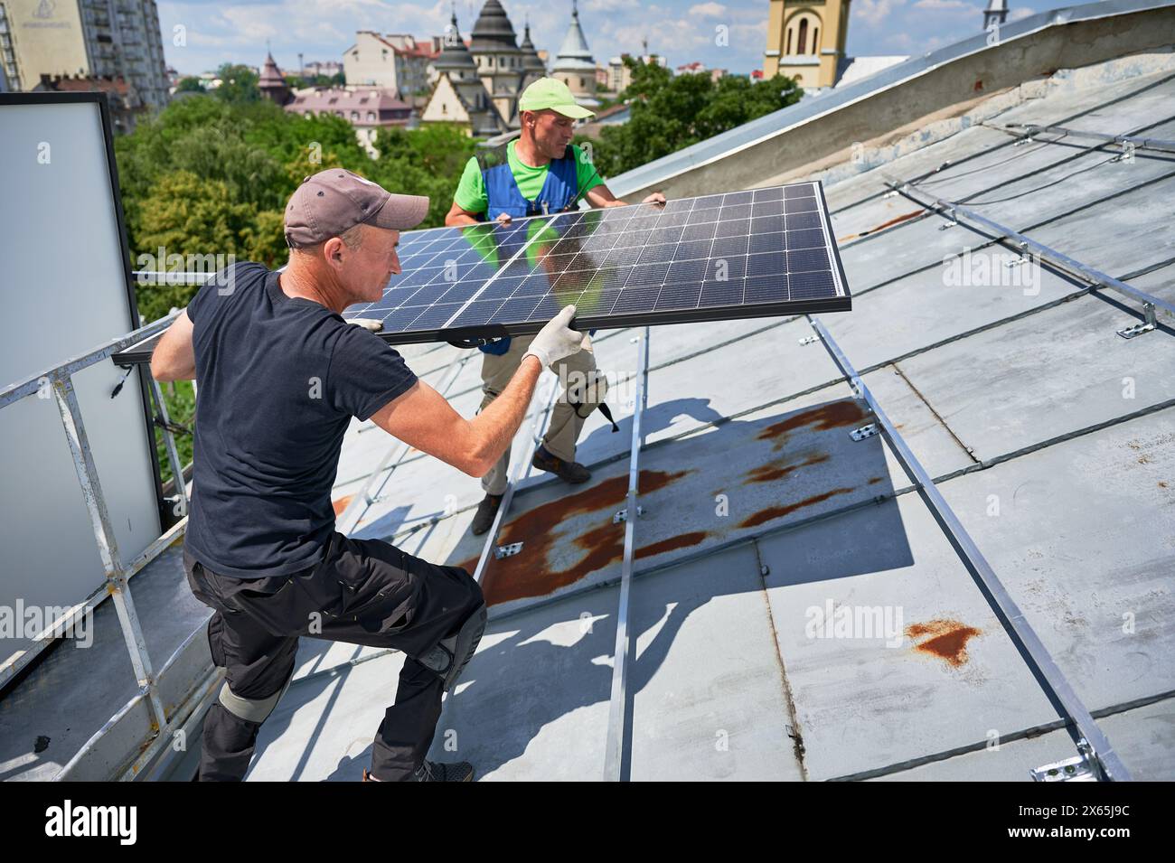 Workers building solar panel system on metal rooftop outdoors ...