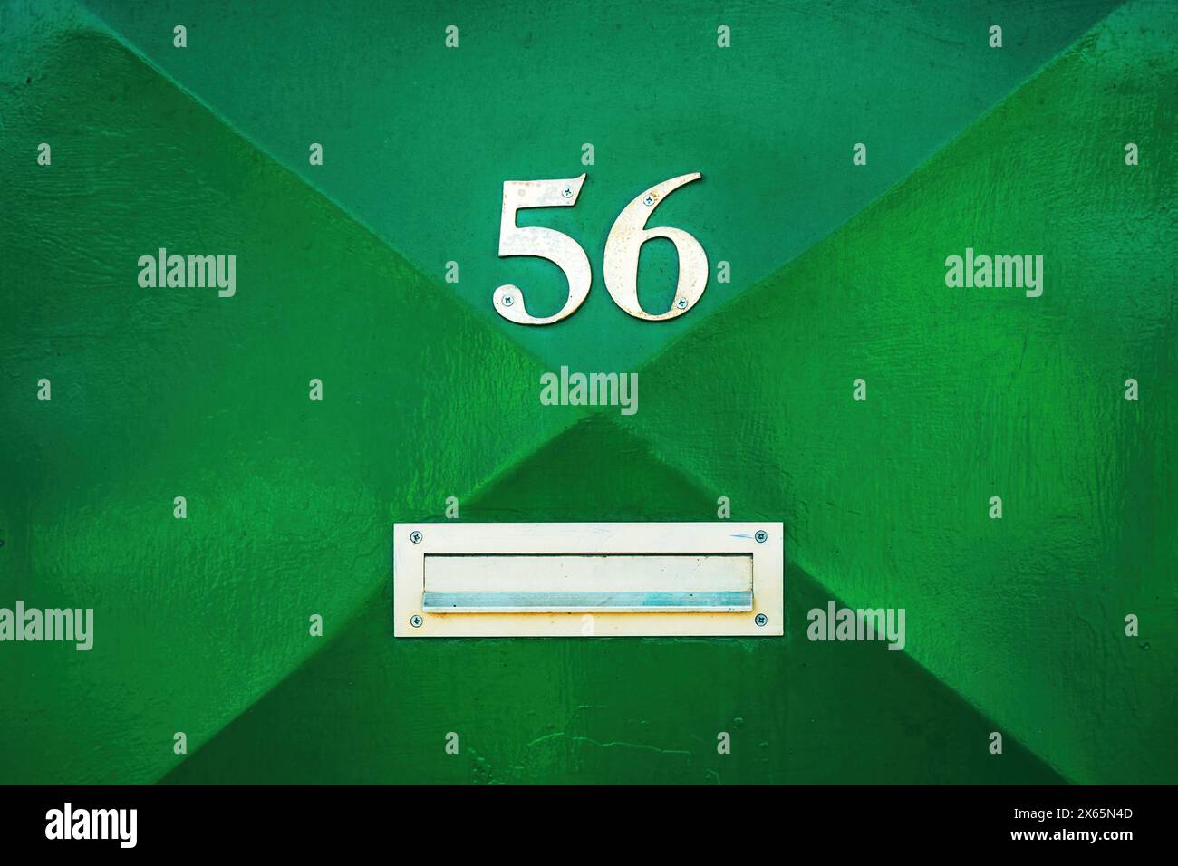 House number 56 on green metal door and mailbox slot. Fifty six in worn ...