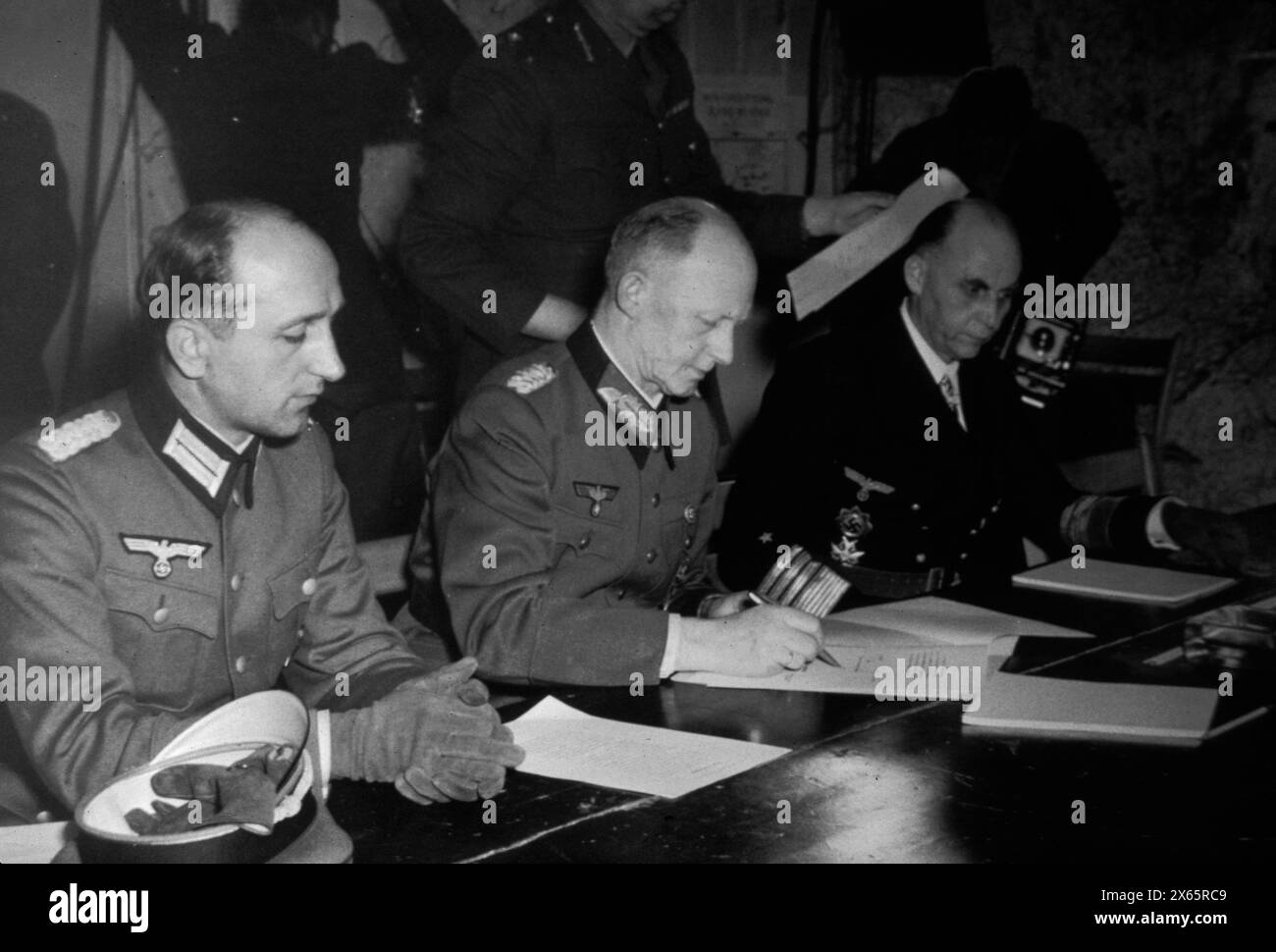 German General Alfred Jodl (center) signs the unconditional surrender ...