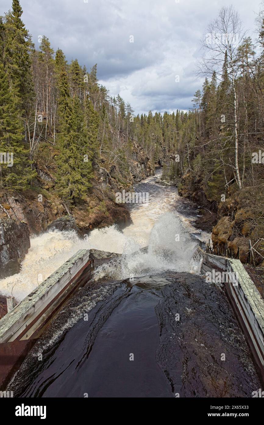 Log floating flume at Auttiköngäs waterfall in cloudy spring weather ...