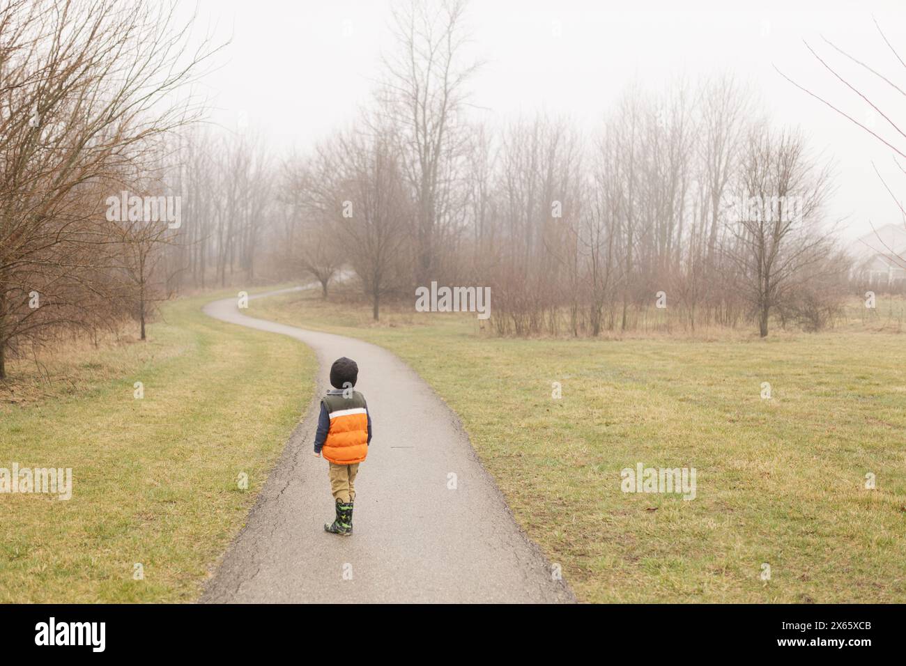 Child walking alone on misty park path Stock Photo - Alamy