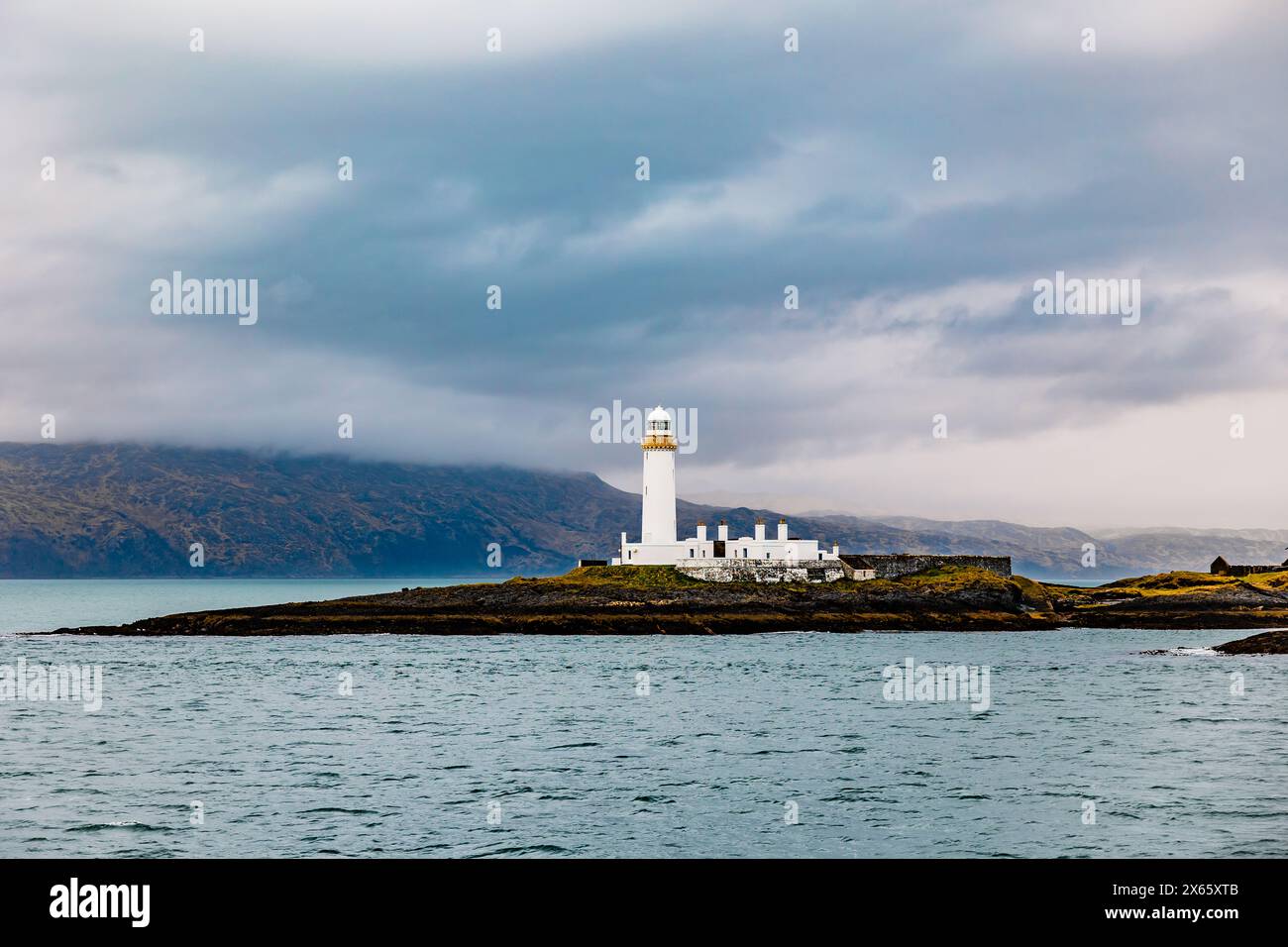 White Lighthouse on an Island Surrounded by Teal Water on a Cloudy Day ...