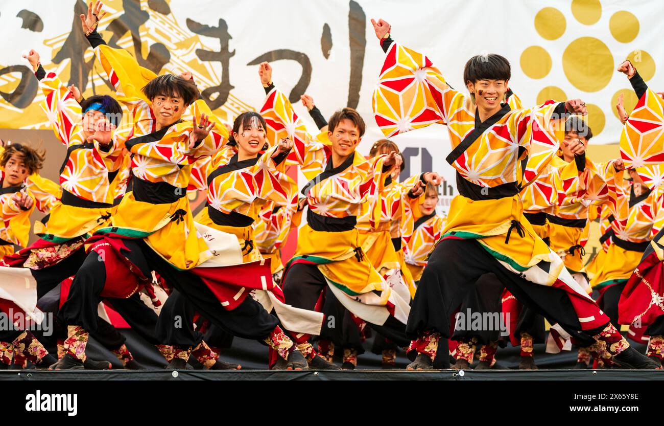 Group of teenage men and women Yosakoi dancers dancing in bright yellow ...