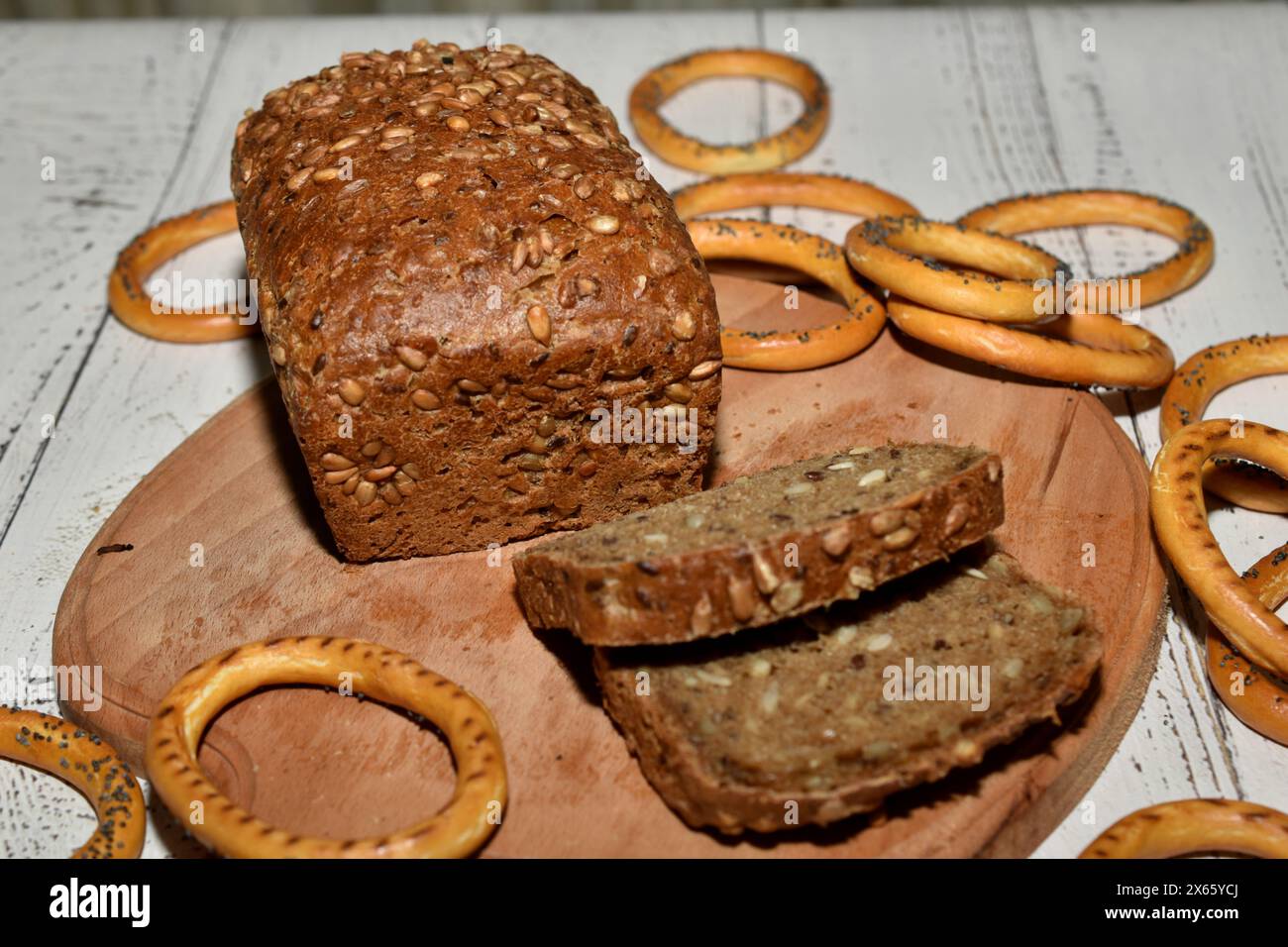 A loaf of bread made from rye flour, pieces and bagels cut from it lie ...