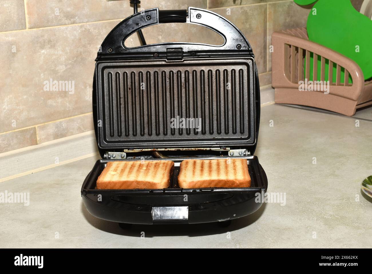The electric grill is open. Toasted bread and toast lie on the ribbed ...