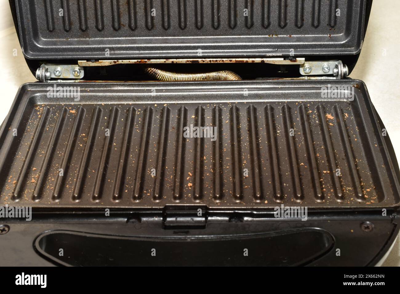 The photo shows an open sandwich maker, with crumbs from cooked toast ...