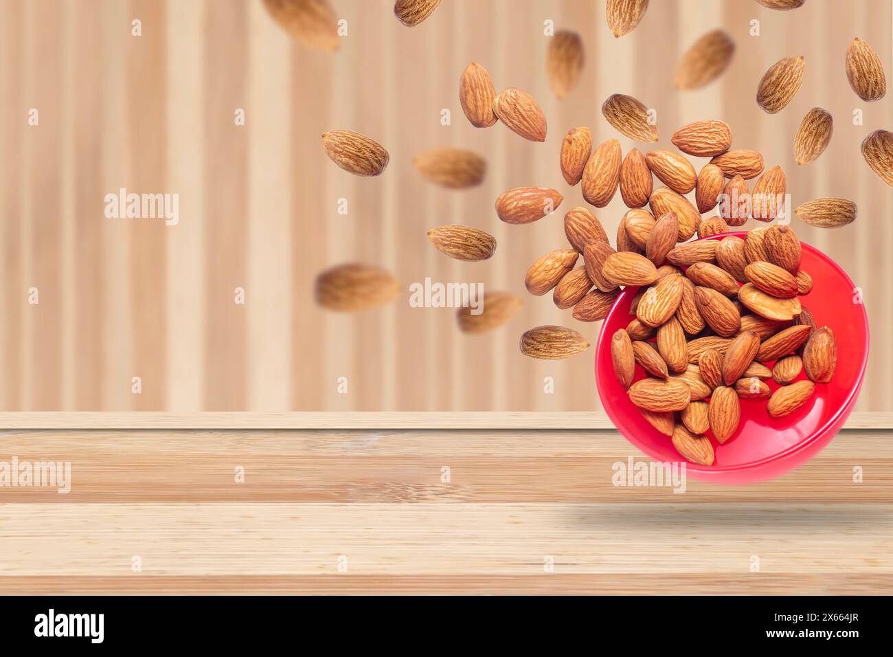 Almonds falling in red bowl on wooden table. Healthy food concept. Copy ...
