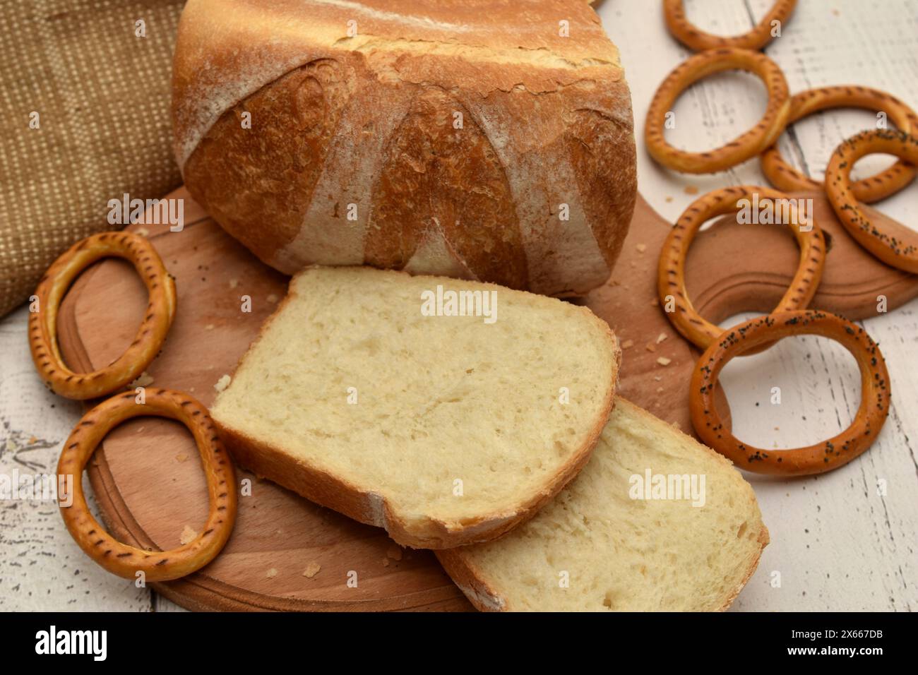 Bread, sliced bread and bagels lie on a cutting board on the table ...