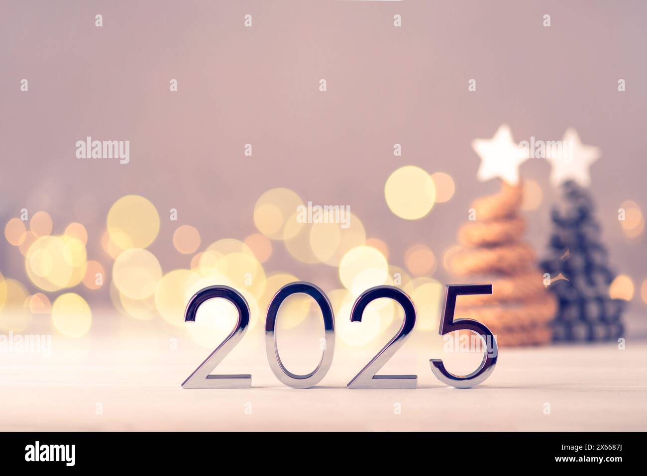 Metal numbers 2025 on a white table with Christmas trees and bokeh lights. Happy New Year 2025 ...