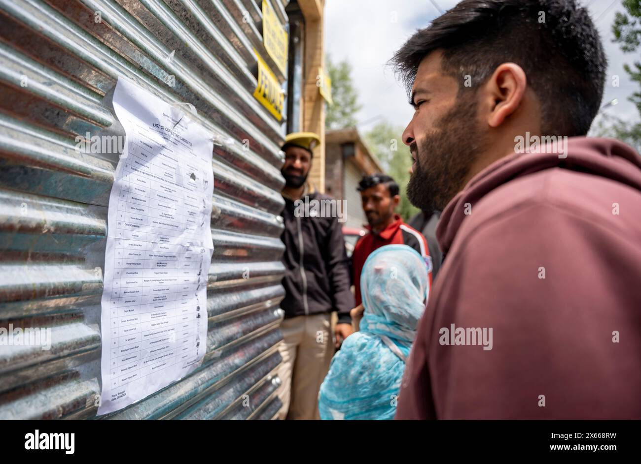 A Kashmiri voter is seen reading a list of election candidates before ...