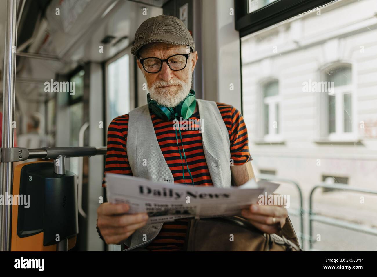 Elderly man traveling through the city by bus, reading newspaper ...