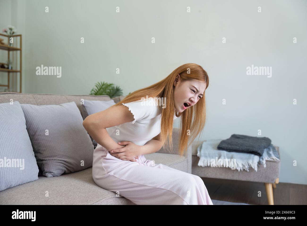 asian woman suffering from stomach ache, undergoing belly pain and ...